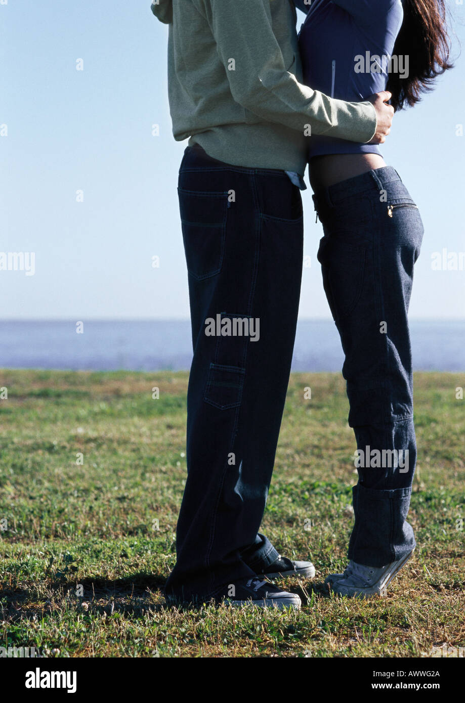 Young couple embracing, waters edge in distance, lower section Stock ...