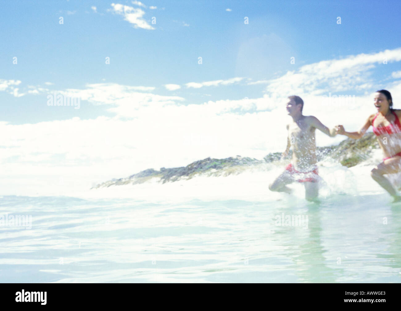 Couple running into ocean Stock Photo - Alamy