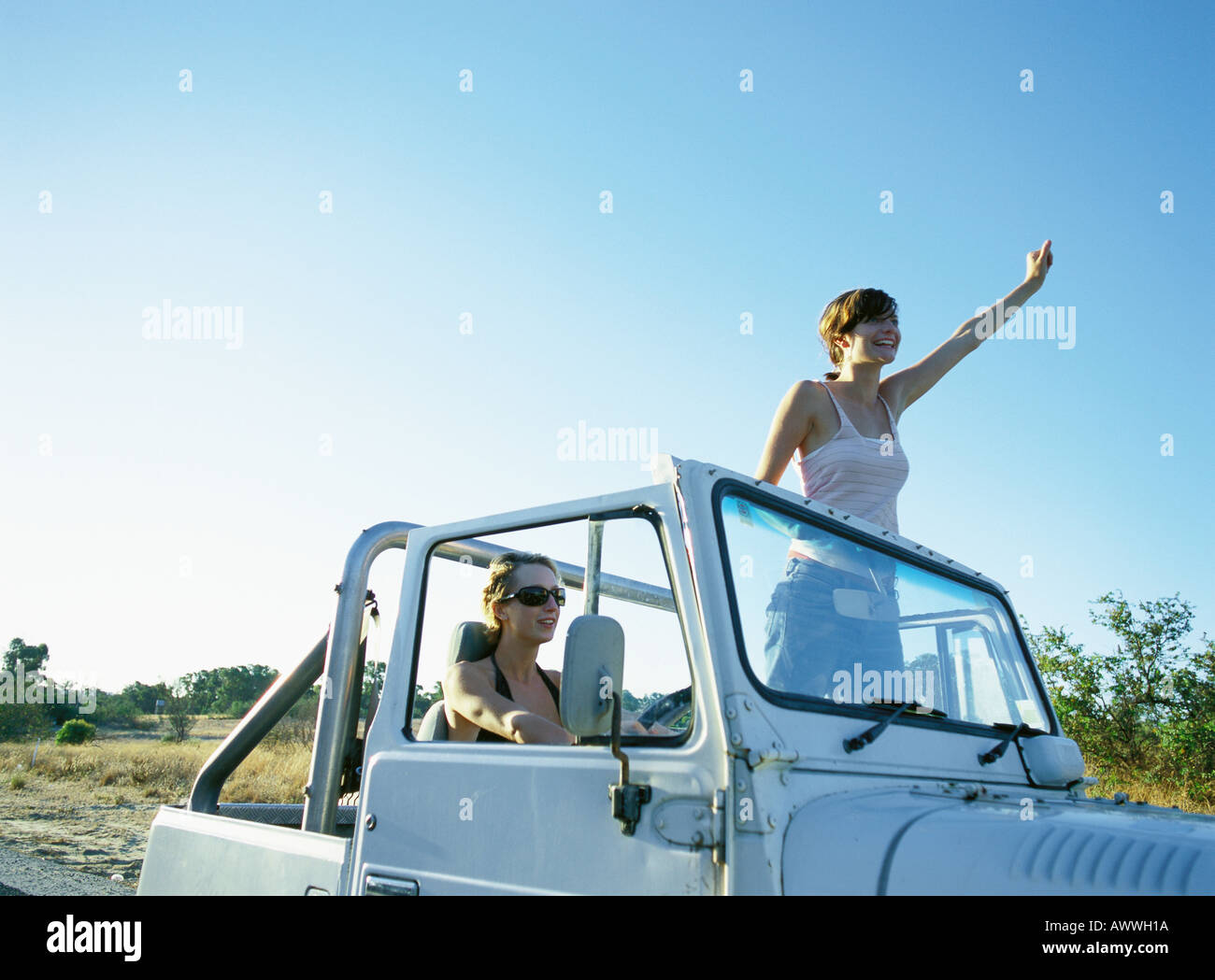 Two women in 4x4 vehicle, one standing up, waving Stock Photo - Alamy
