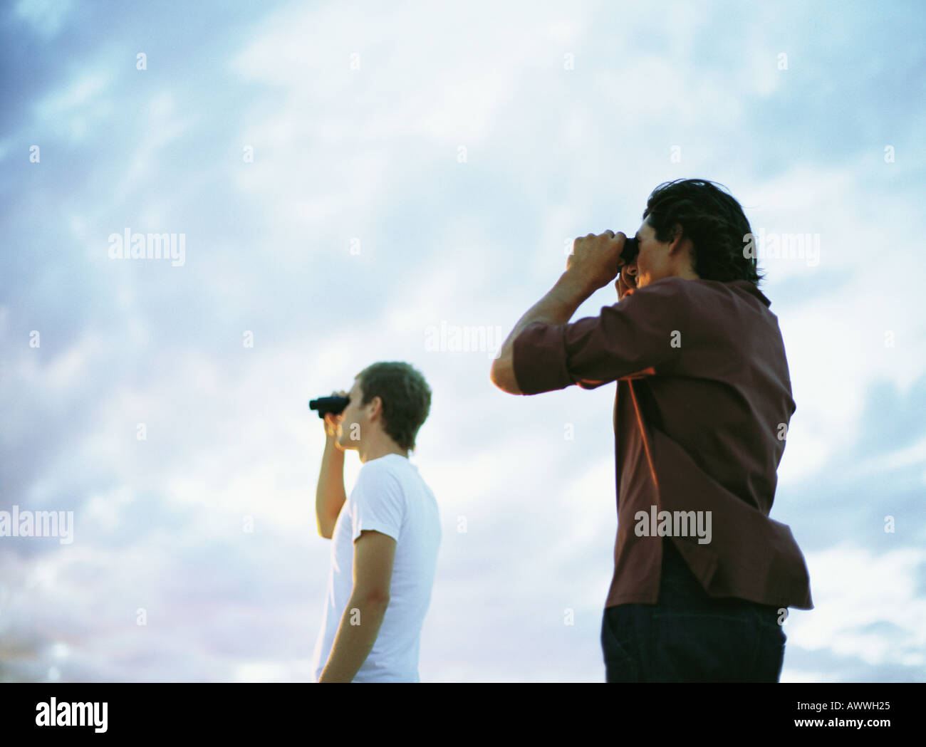 Two people looking through binoculars, low angle view Stock Photo - Alamy