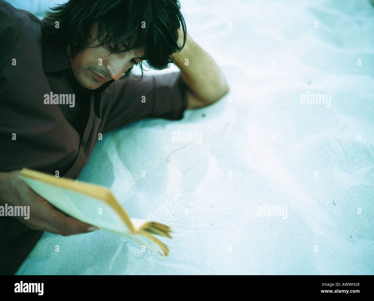Man lying on sand, reading, close-up Stock Photo - Alamy