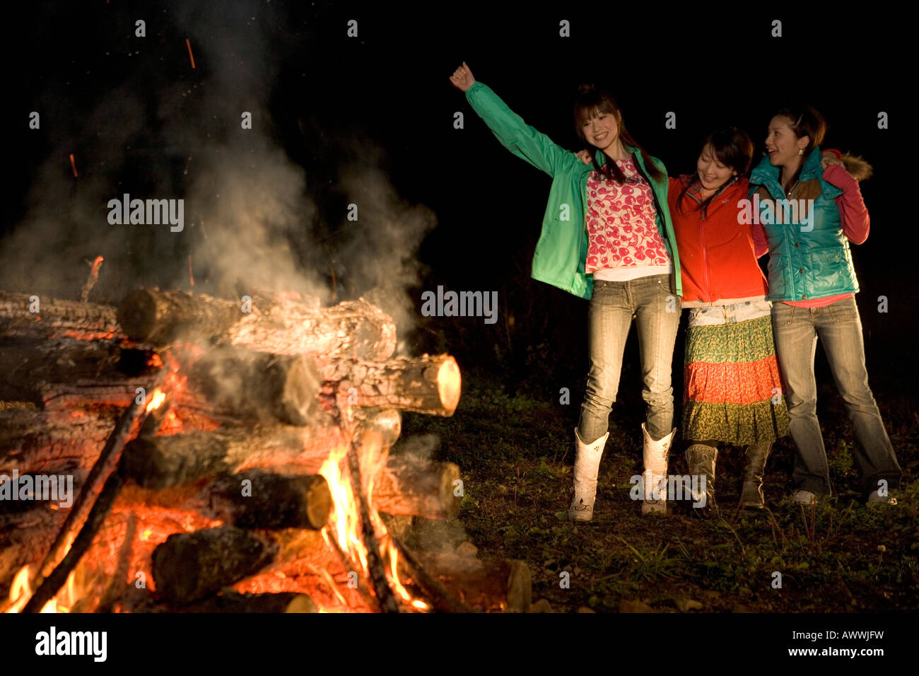 Friends by campfire at night Stock Photo - Alamy