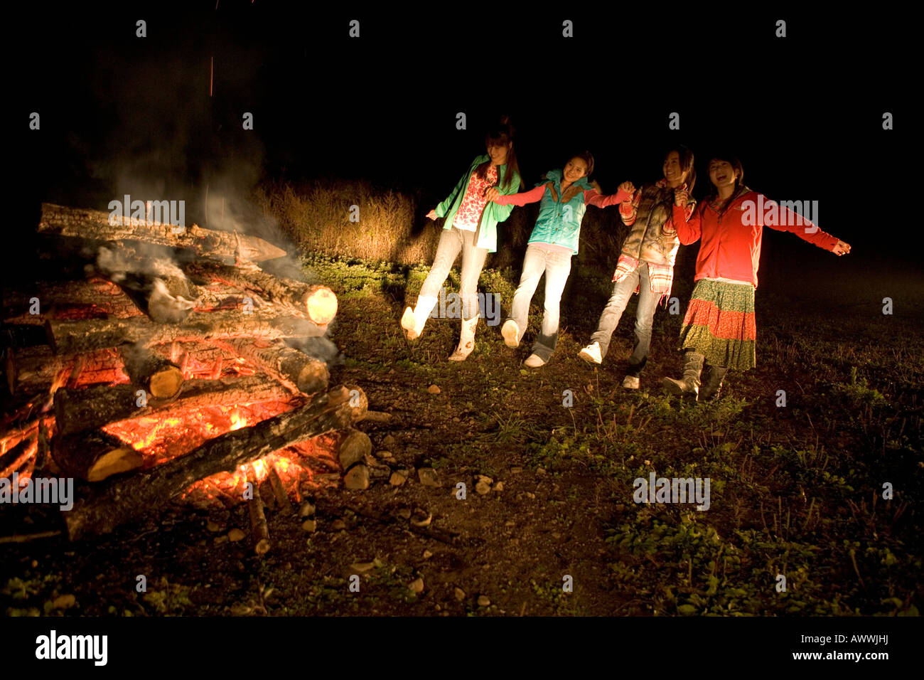 Friends by campfire at night Stock Photo - Alamy