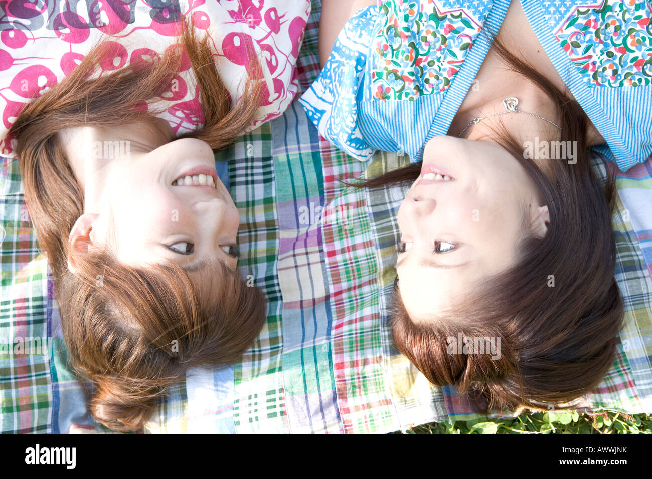 Two young women lying on blanket and looking in eyes Stock Photo - Alamy