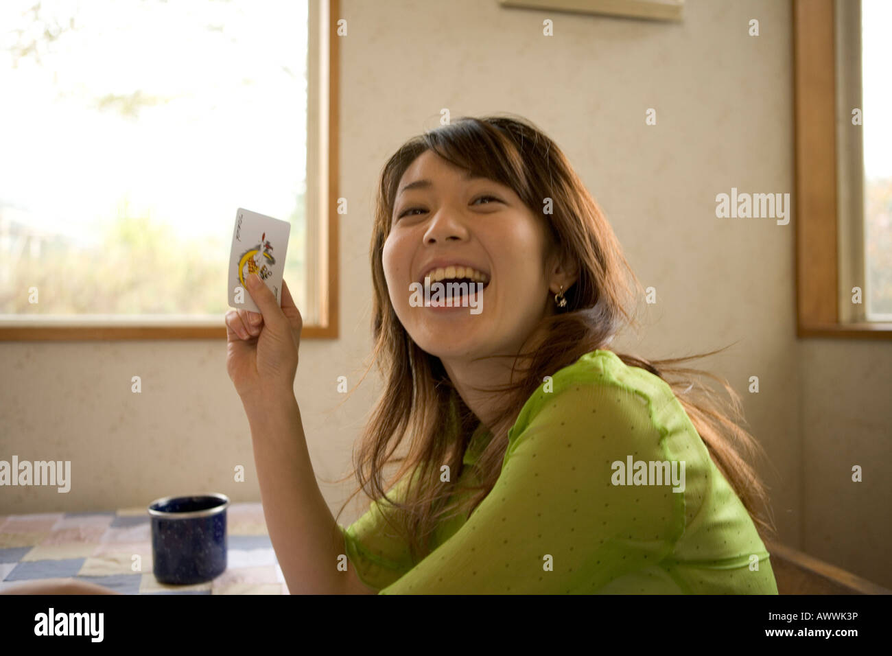 Young woman holding playing card and laughing Stock Photo - Alamy