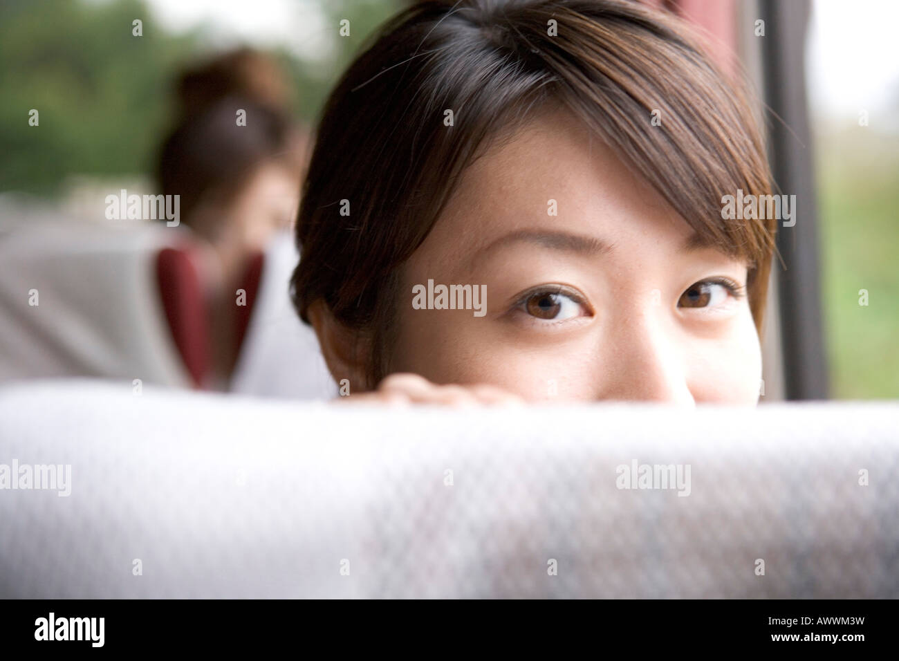 Young woman peeking from behind seat Stock Photo - Alamy