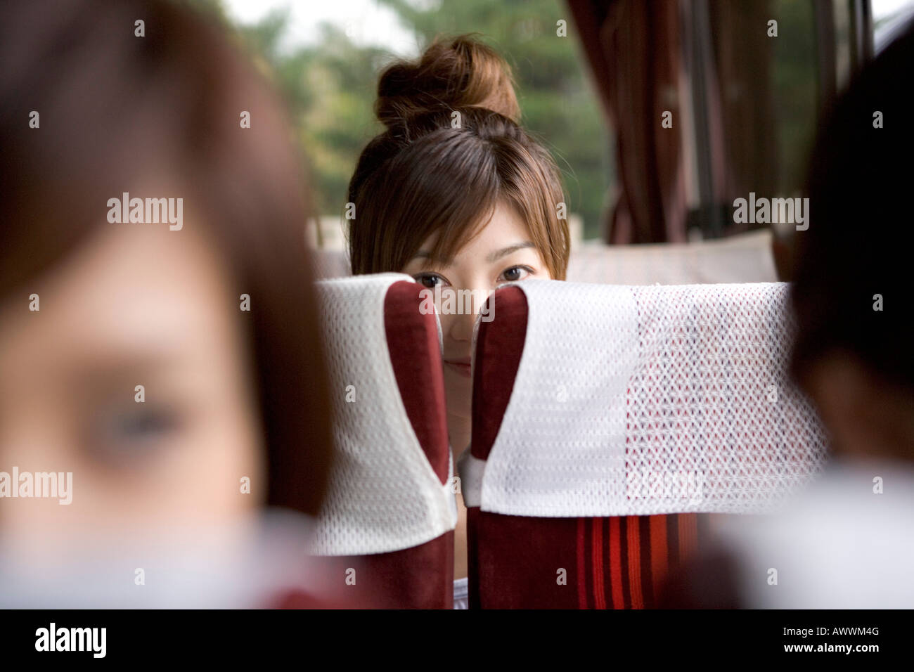 Young woman peeking from behind seat Stock Photo - Alamy