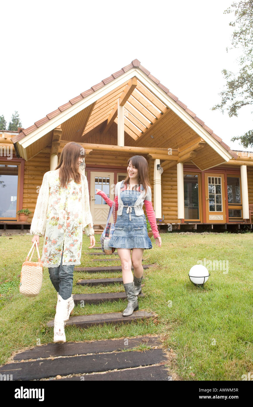 Two young women walking outside house Stock Photo - Alamy