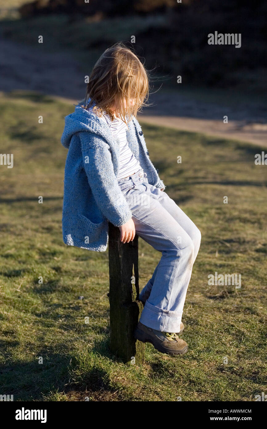 A girl sits on a post in the outdoors Stock Photo - Alamy