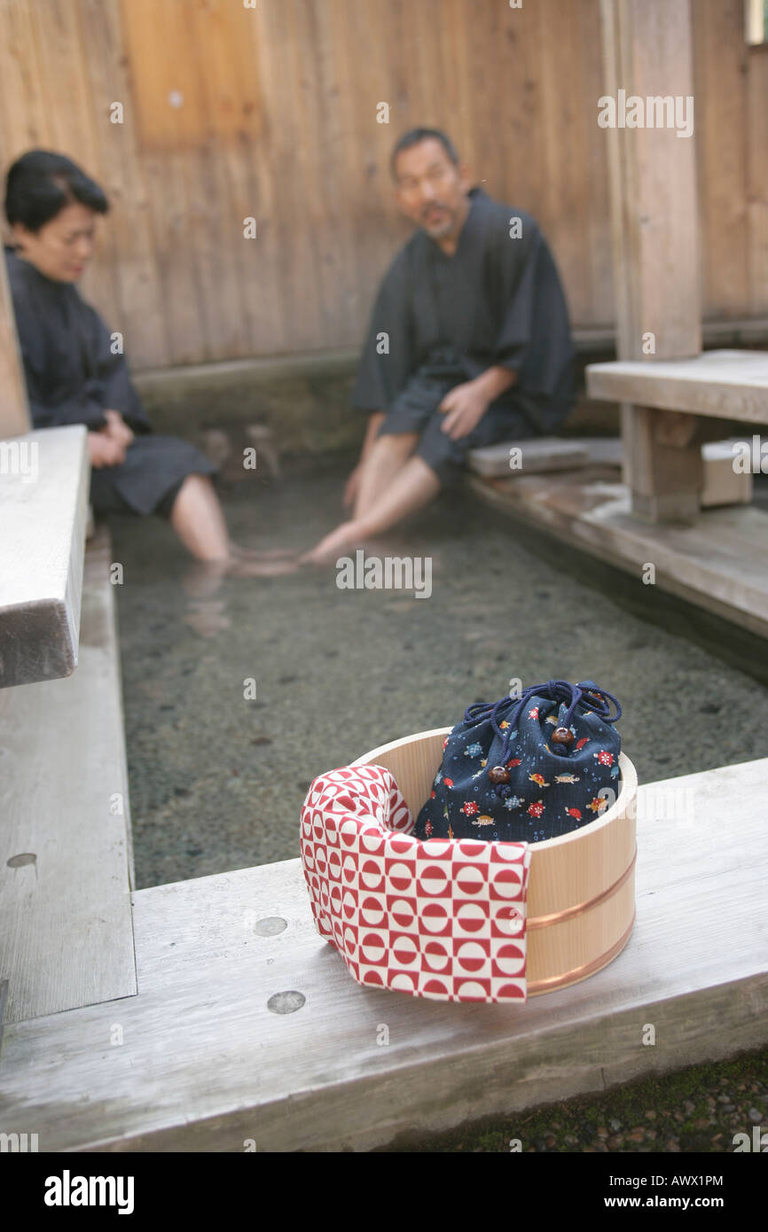 Wooden bucket on bench in japanese spa with elderly couple on ...