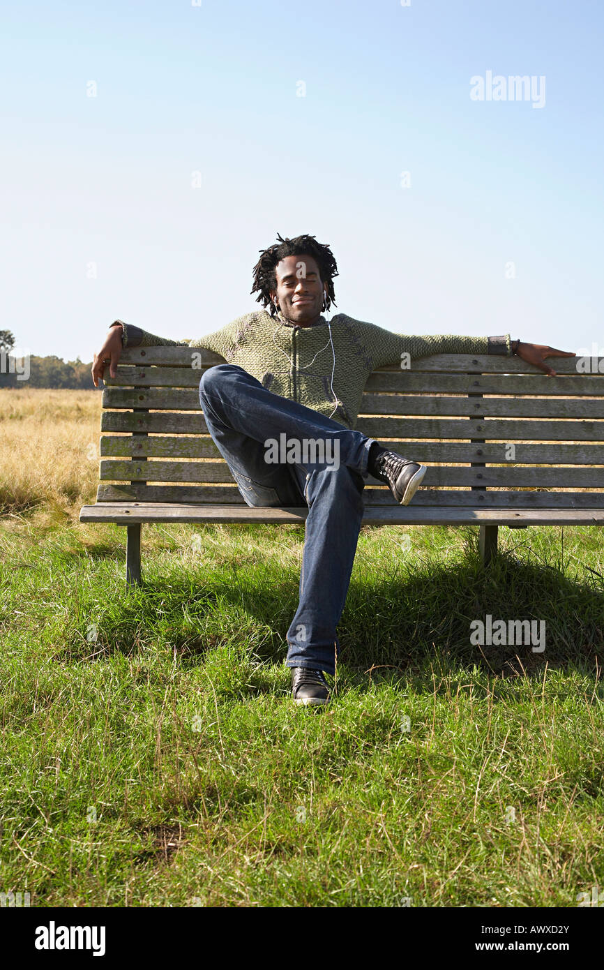 Man sitting on bench in field Stock Photo - Alamy