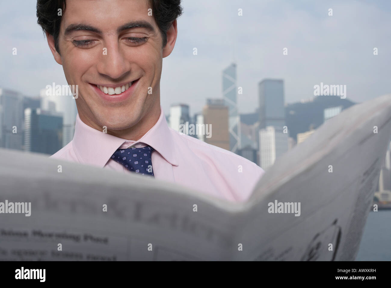 Close-up of businessman reading newspaper, city skyline in background ...