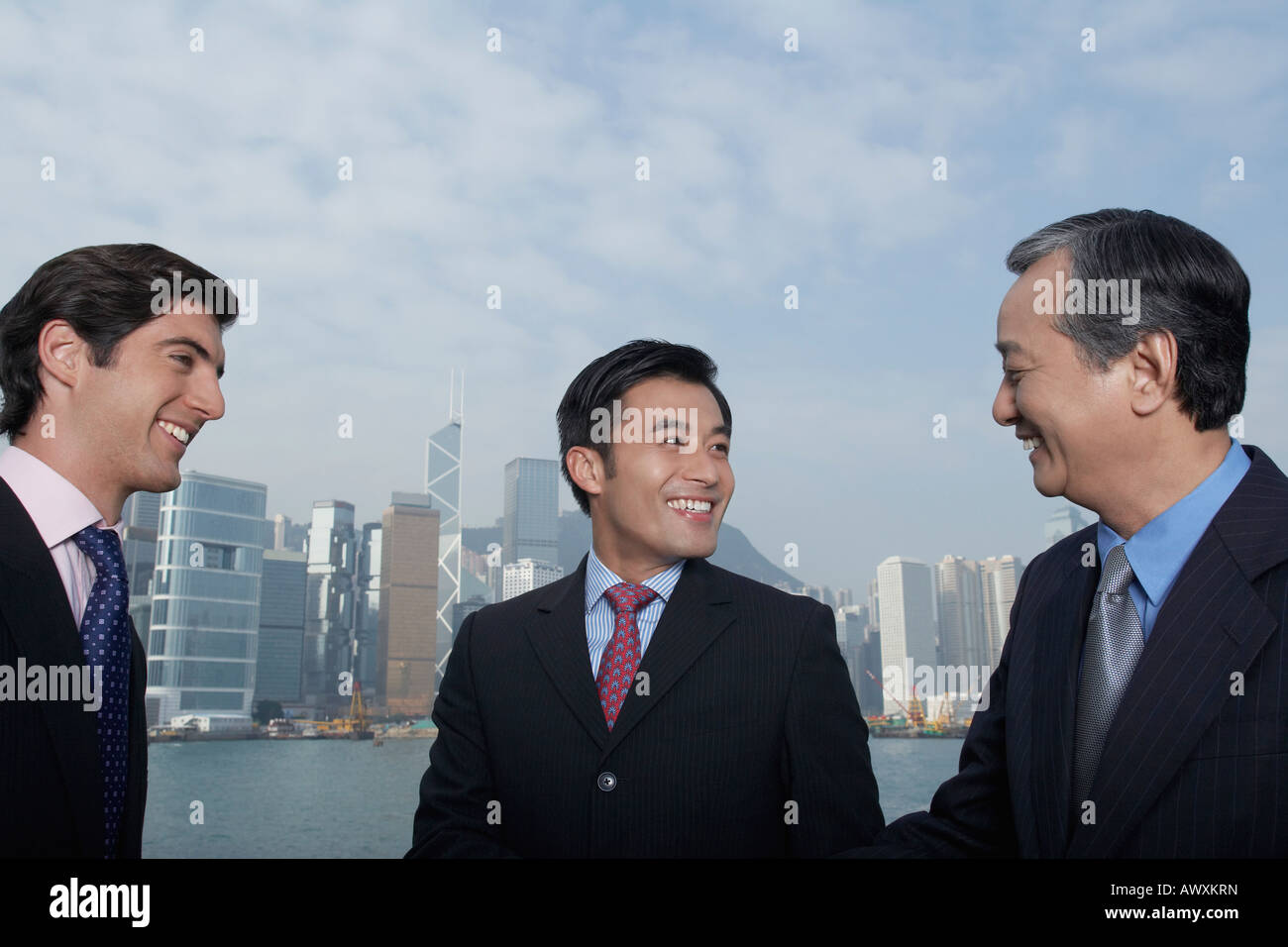 Three business men smiling, office buildings in background Stock Photo ...
