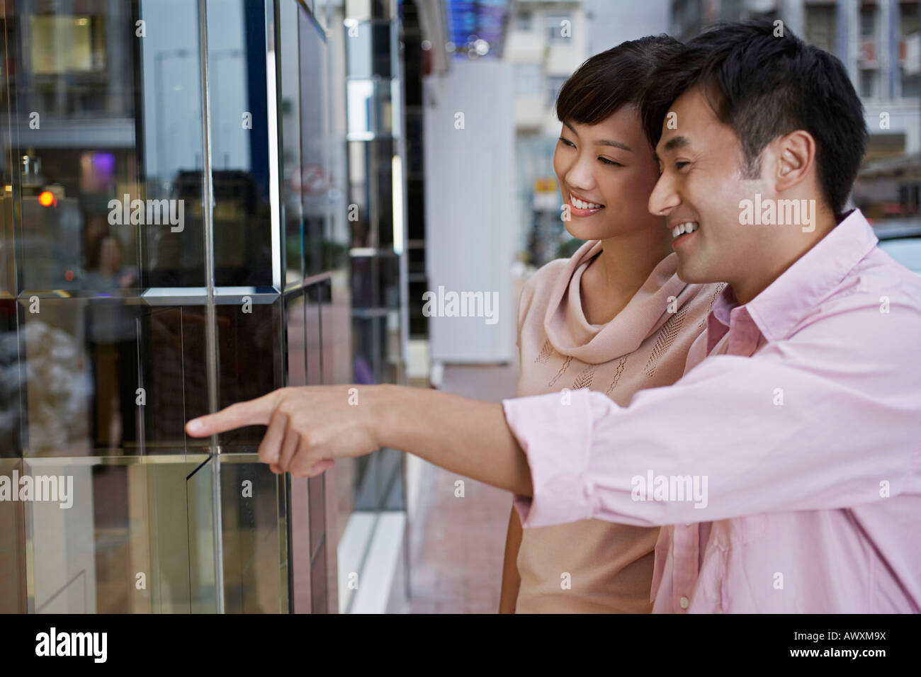 Couple looking through shop window at display Stock Photo - Alamy