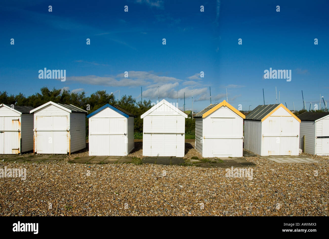 Front view of beach huts straight on with the blue sky and pebble beach ...