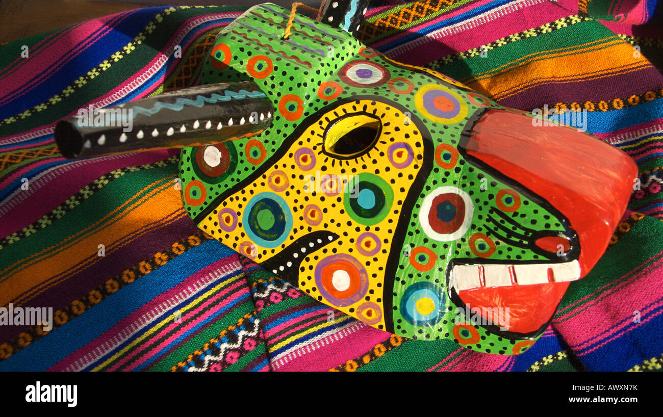 Guatemalan wooden dance mask against a multicoloured textile ...