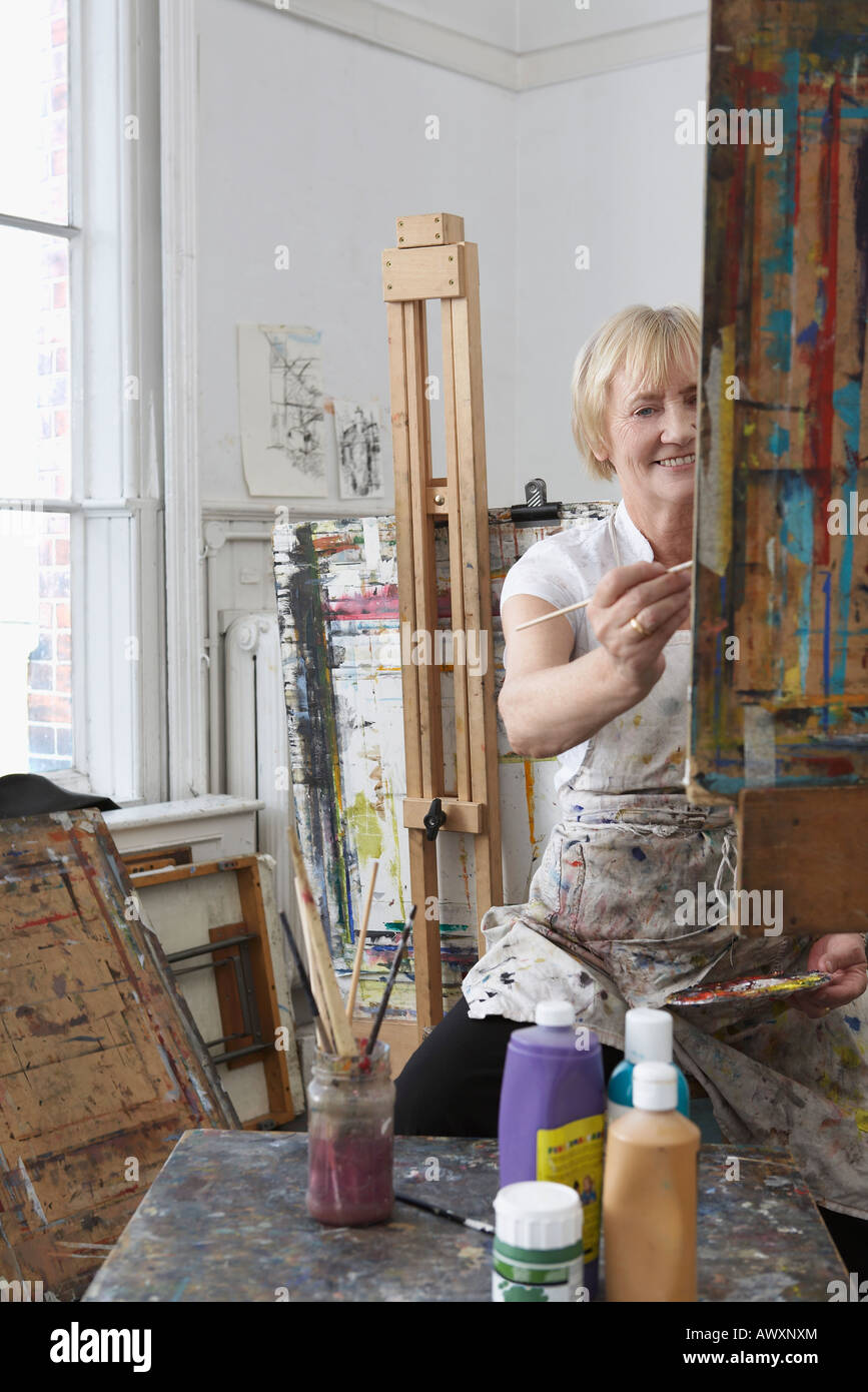 Mature female artist painting at easel in art studio Stock Photo - Alamy