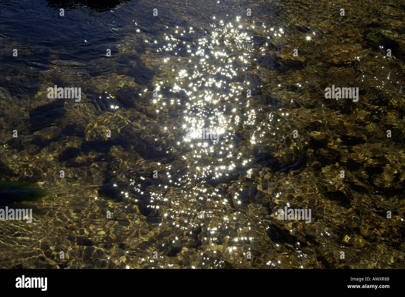 Stone bed and sun reflections on water stream surface Stock Photo - Alamy