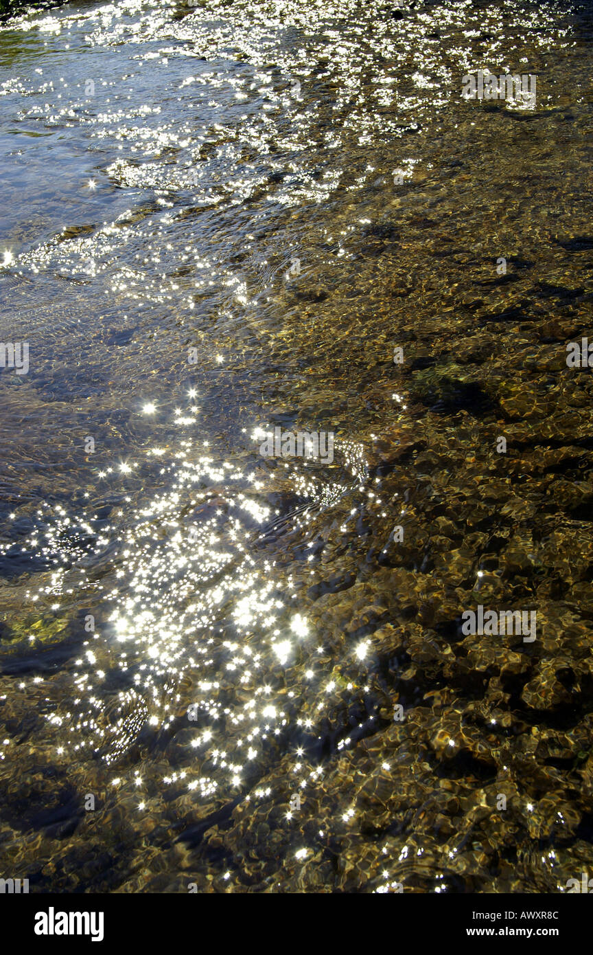Stone bed and sun reflections on water stream surface Stock Photo - Alamy