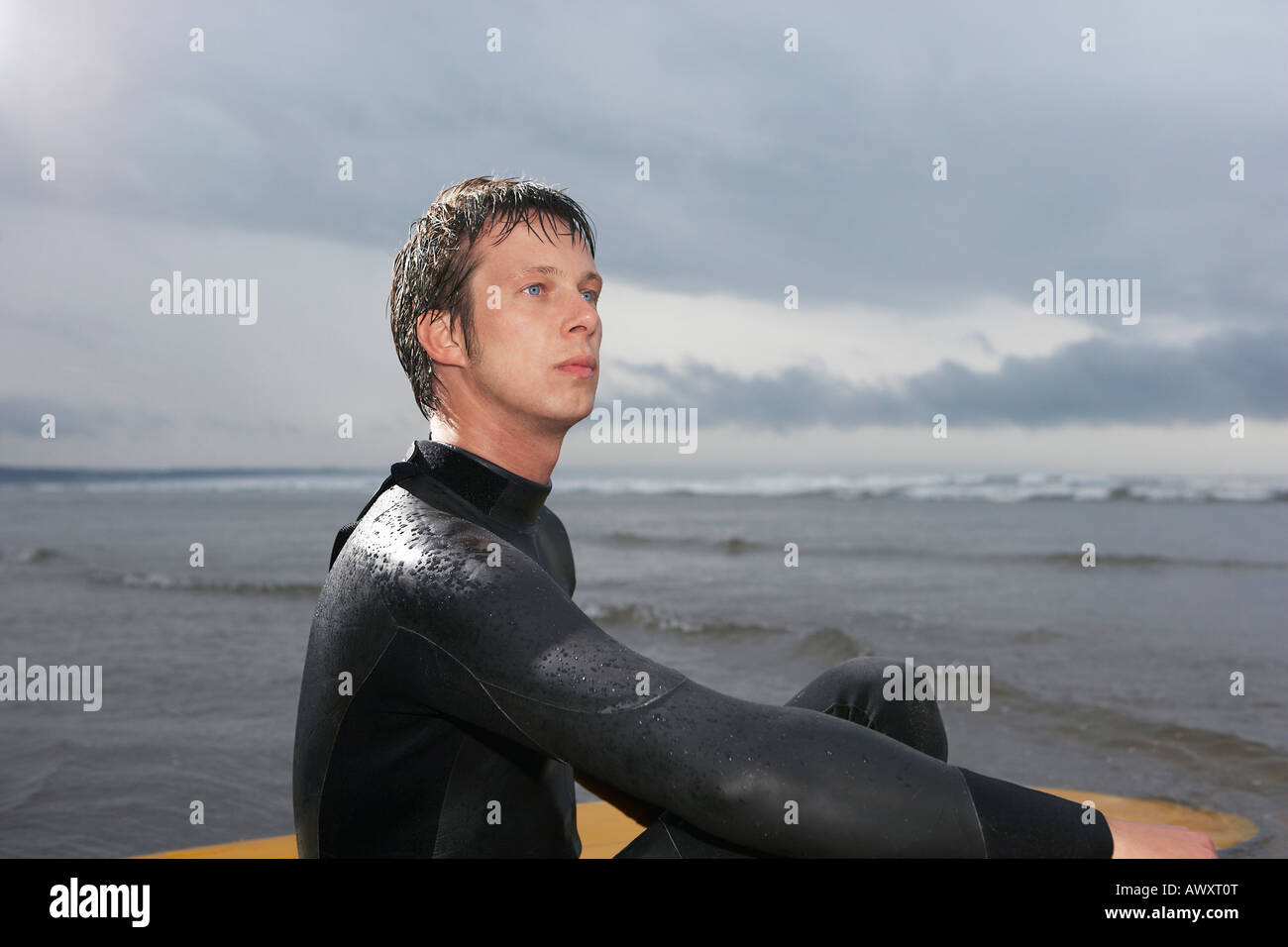 Surfer sitting surfboard in water, side view Stock Photo - Alamy