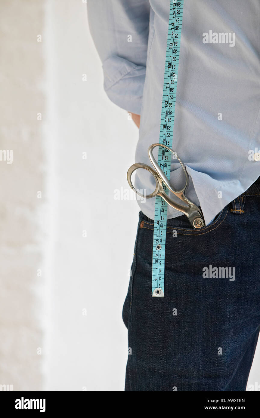 Tailor with scissors in pocket and measuring tape, standing indoors ...