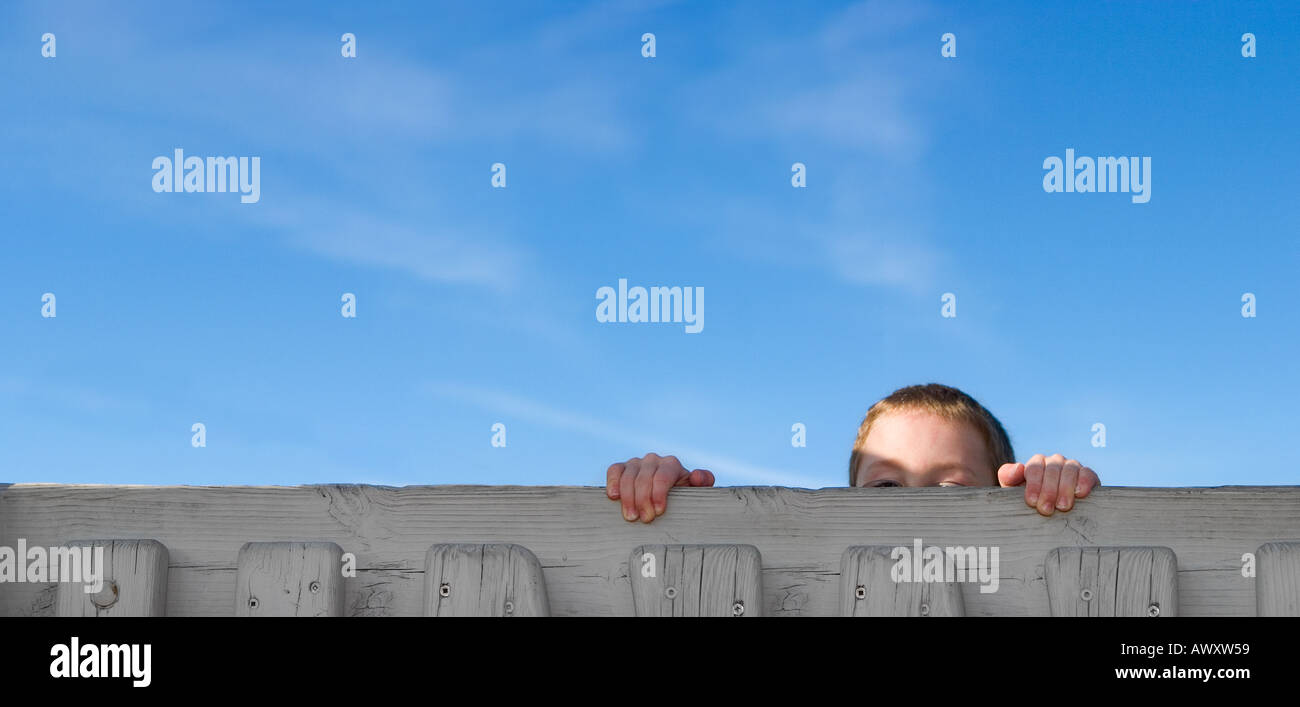 little boy peeking over a fence with just the top half of his face and ...