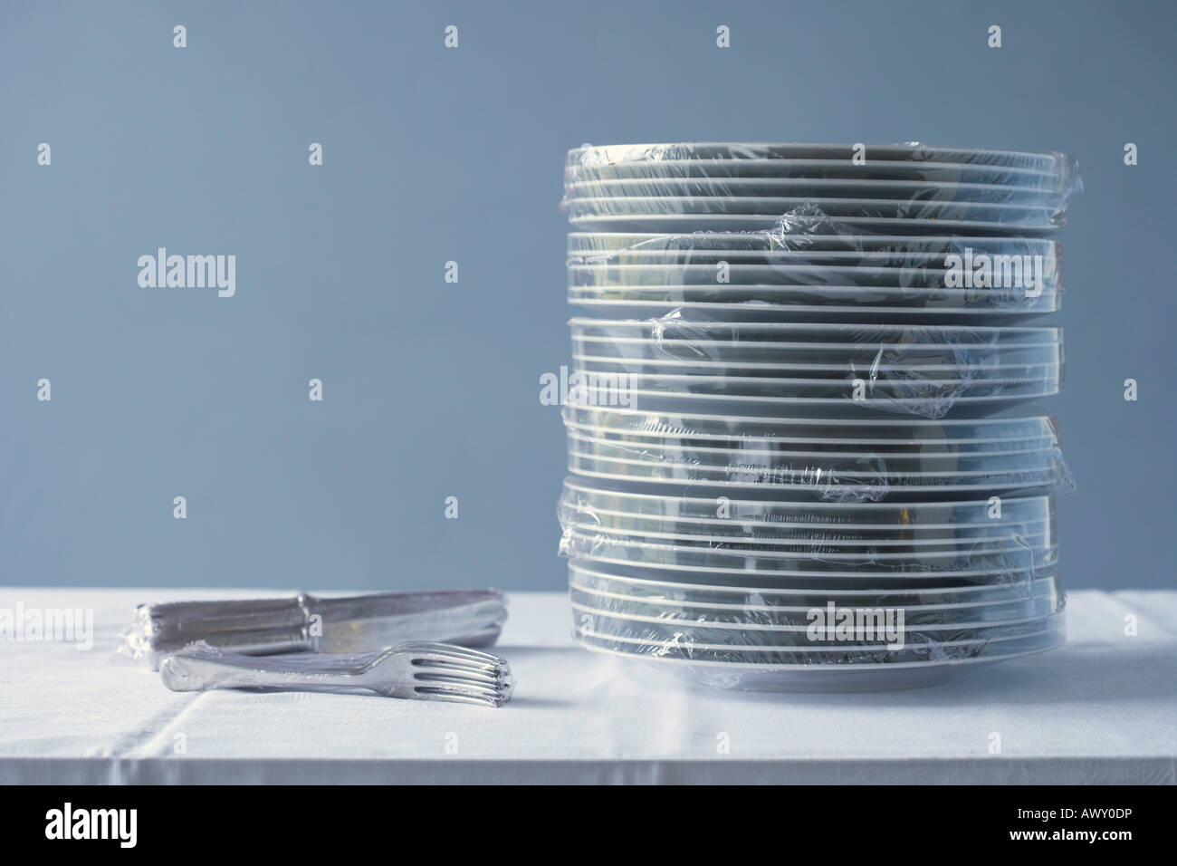 Stack of plates and cutlery wrapped in plastic on table Stock Photo - Alamy