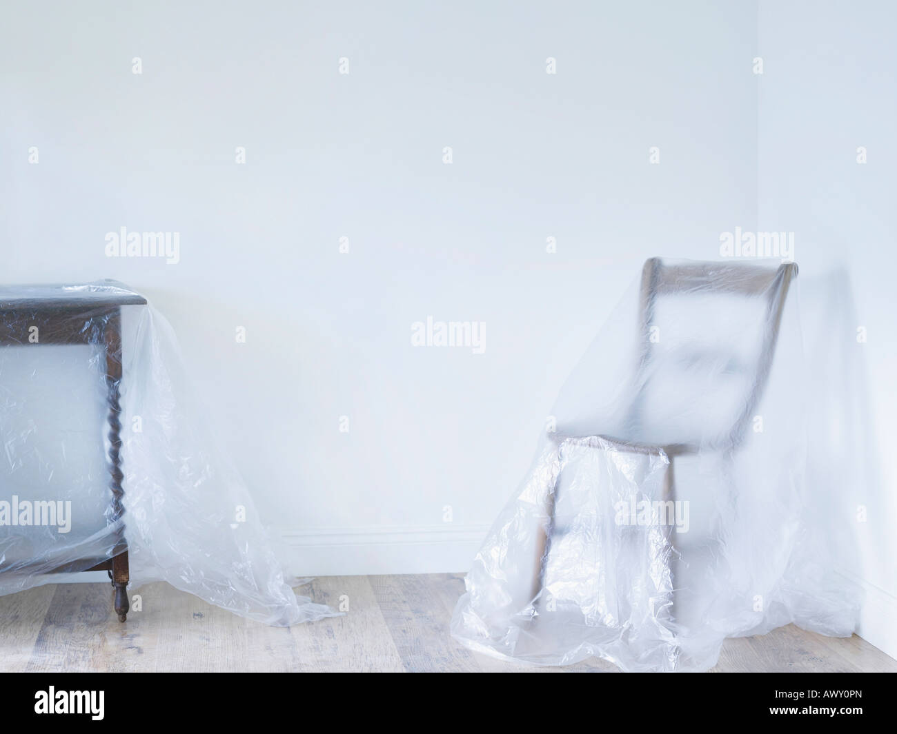 Chair and table covered by plastic in empty room Stock Photo - Alamy