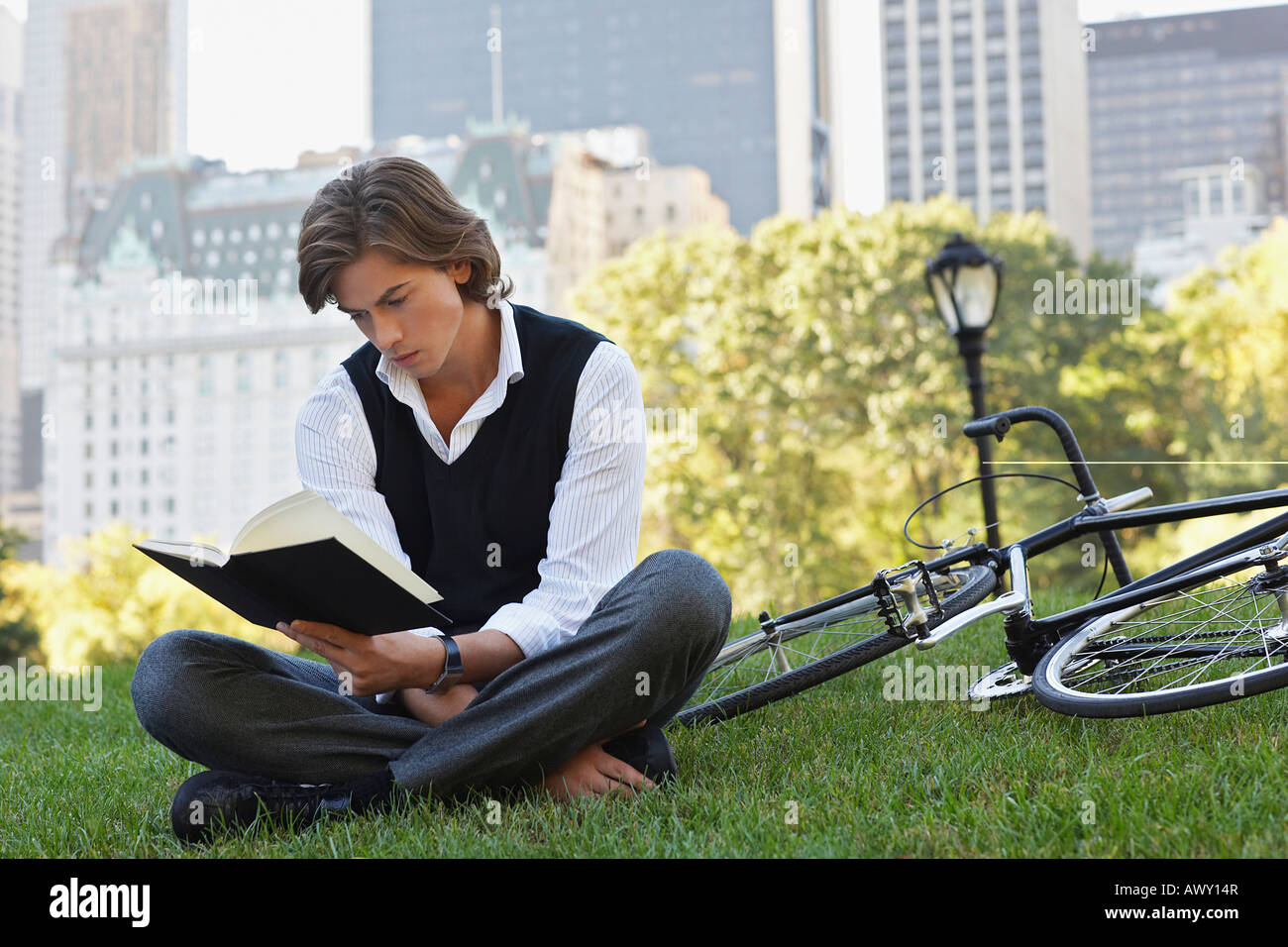 Man sitting on lawn, reading book Stock Photo - Alamy