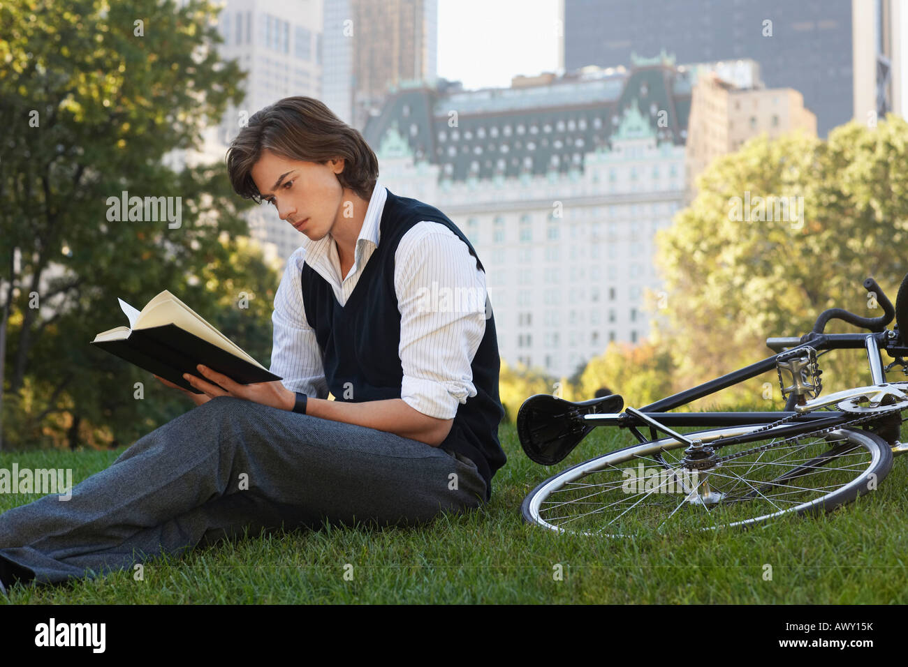 Man sitting on lawn, reading book Stock Photo - Alamy