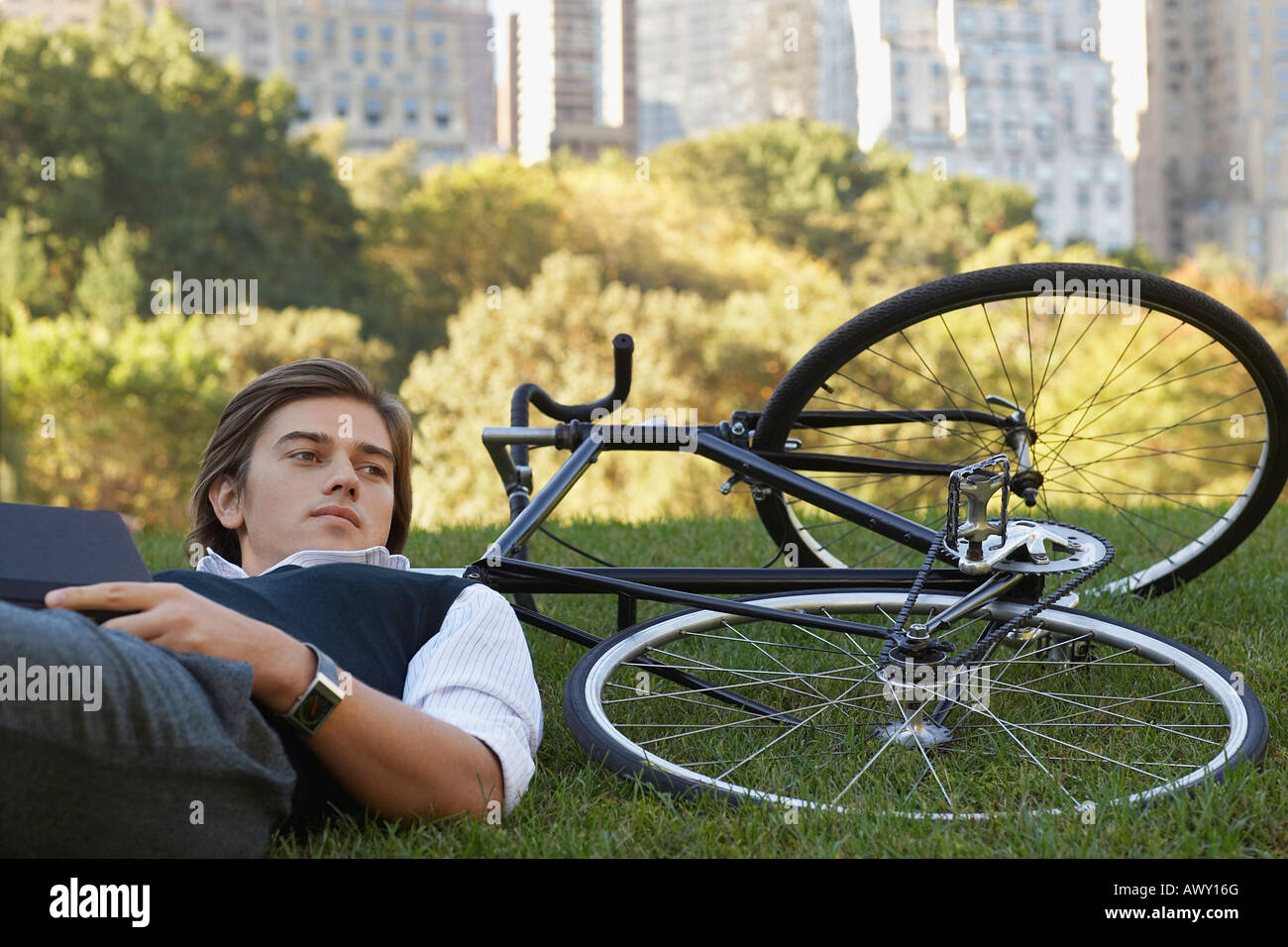 Man leaning against bicycle on lawn Stock Photo - Alamy