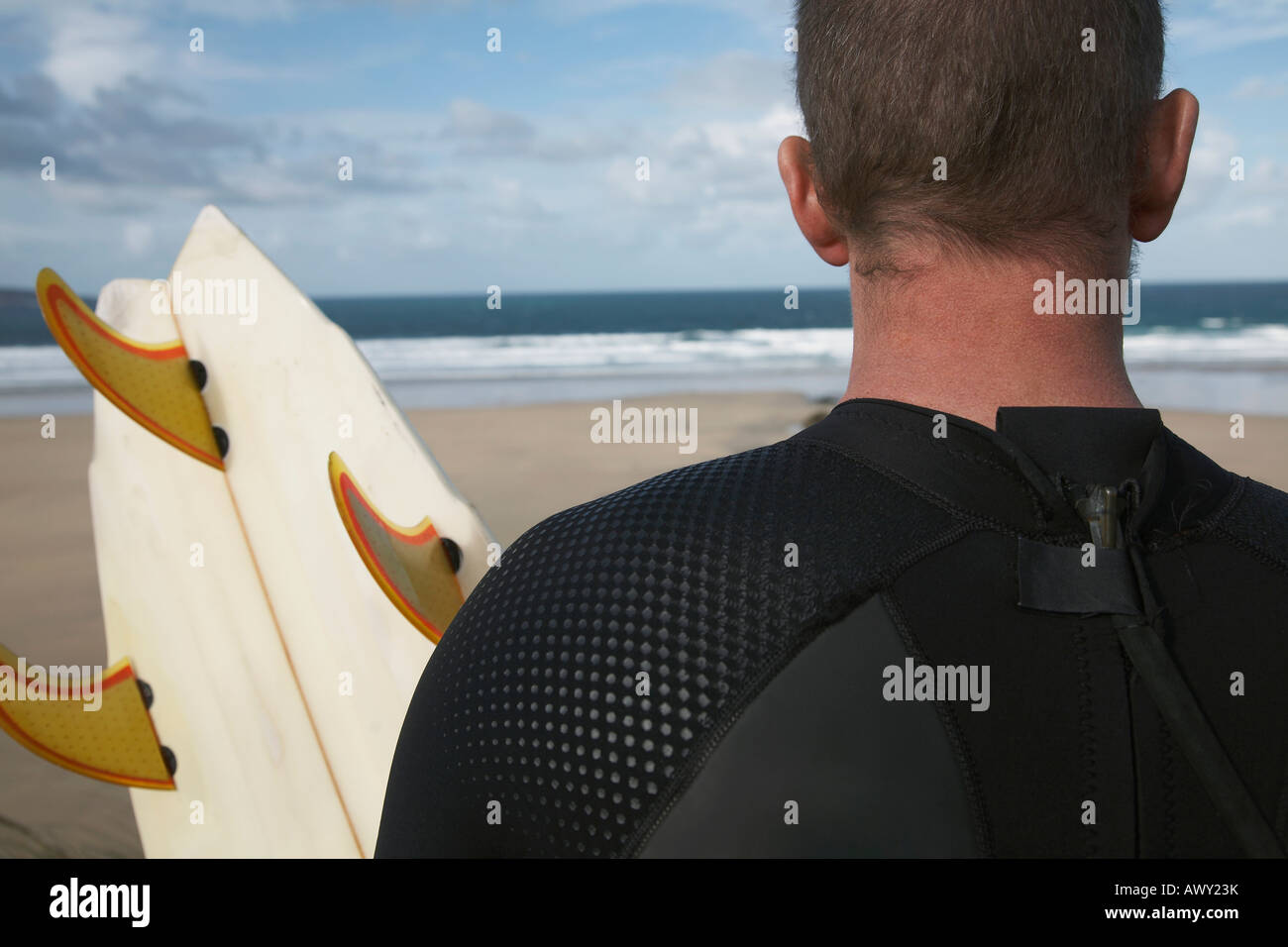 Man holding surfboard on beach looking at sea, back view, close up ...
