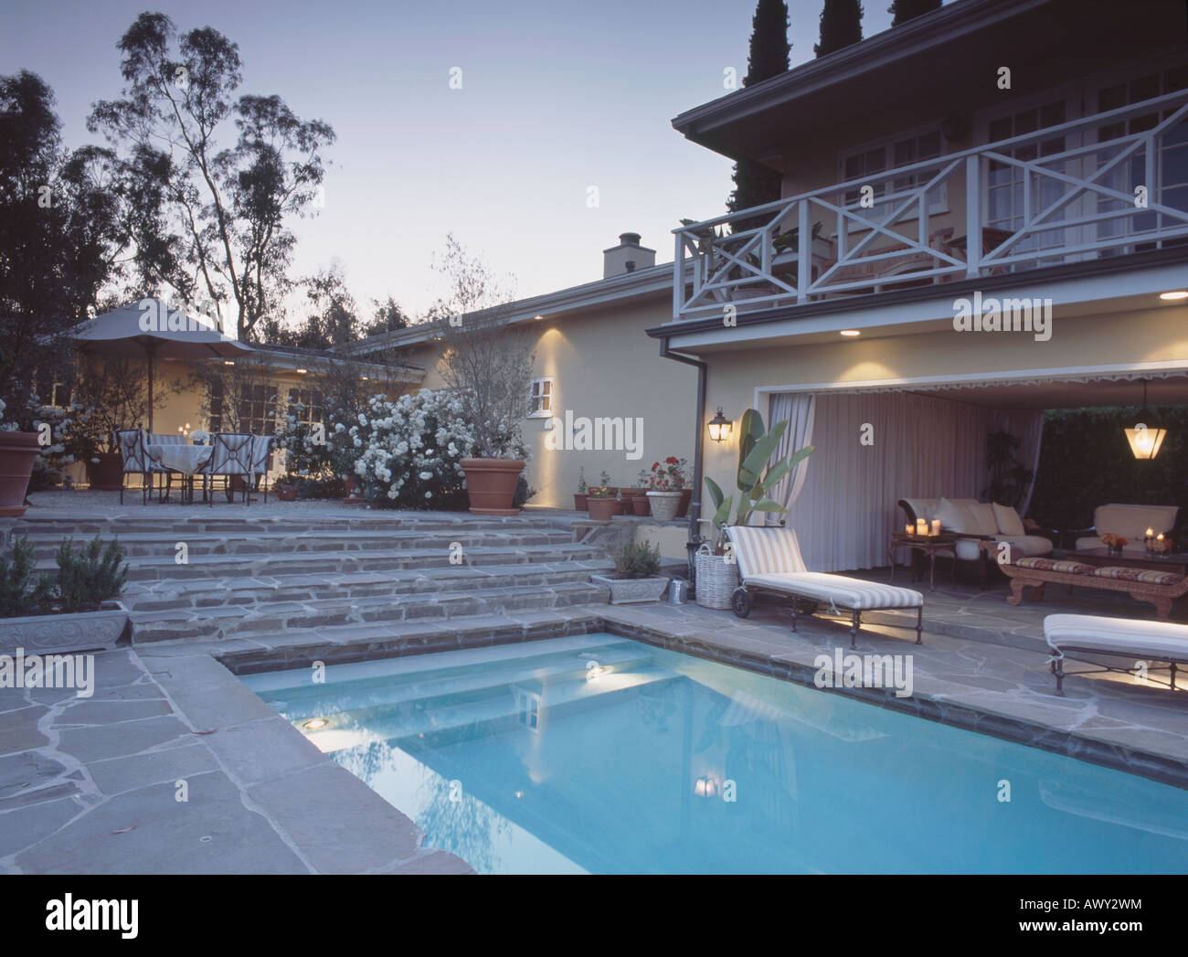 Swimmingpool beside house with balcony above loungers and steps up to ...
