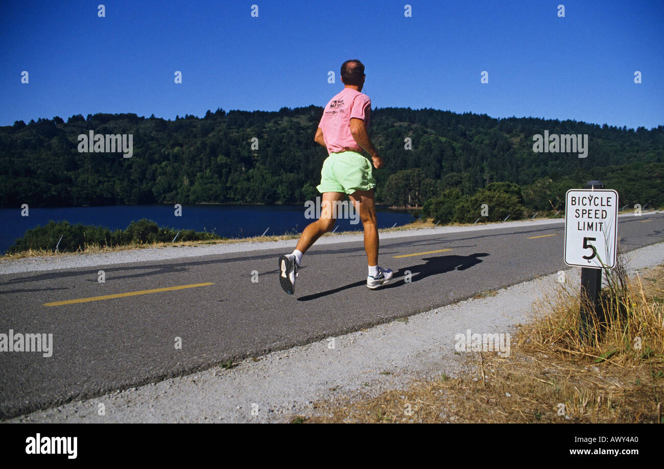 Middle age male runner on bicycle path speed limit sign San Mateo ...