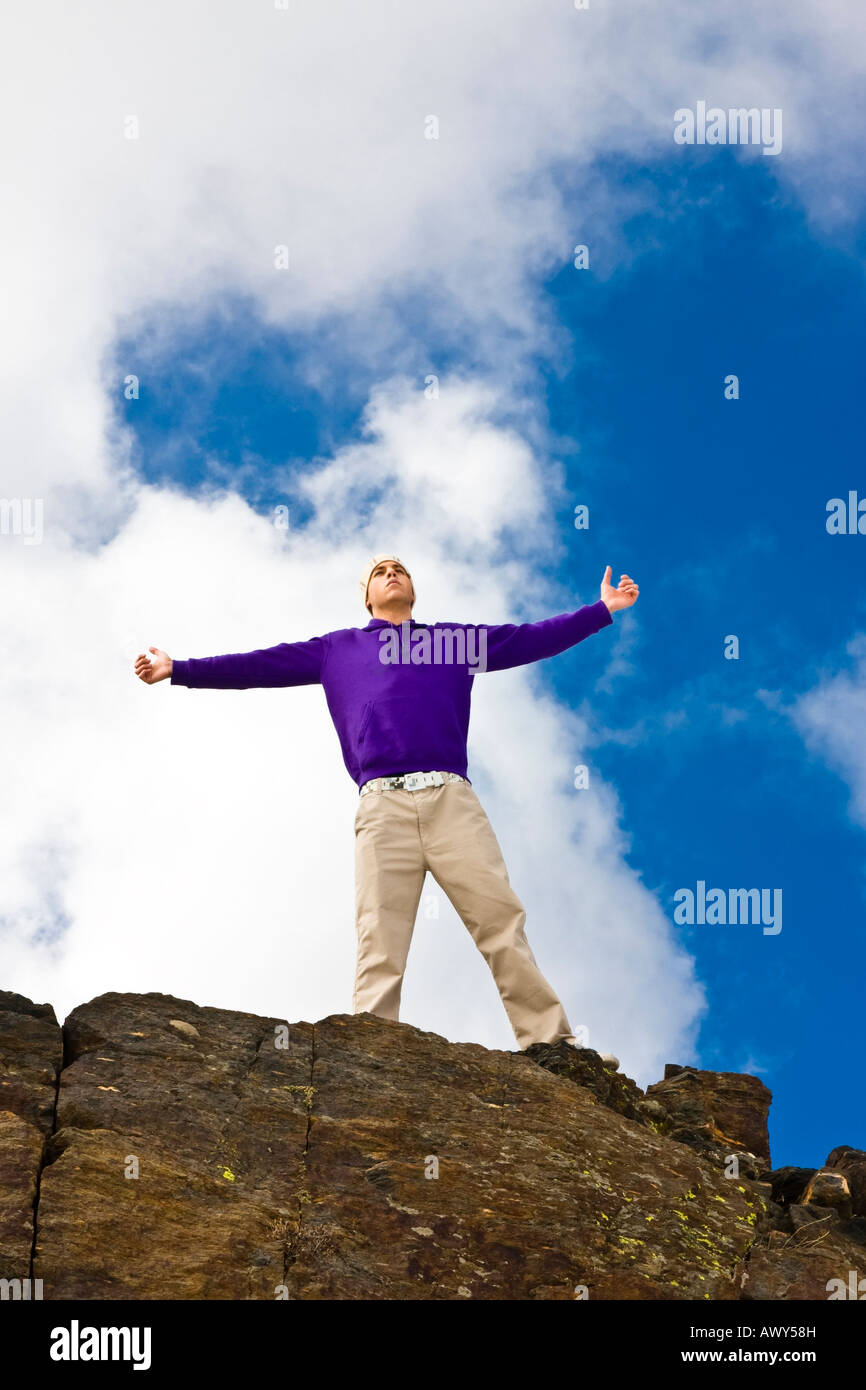 Young man on the rocks in defiant gesture Stock Photo - Alamy