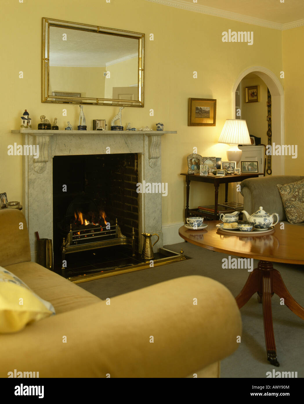 Pastel yellow sofa in front of fireplace in yellow forties livingroom ...