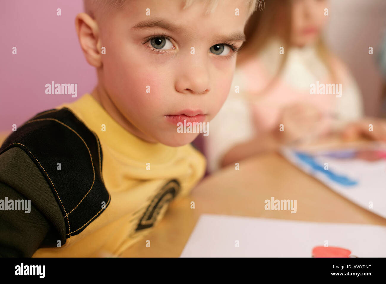 Boy sitting at a table, looking at camera Stock Photo - Alamy