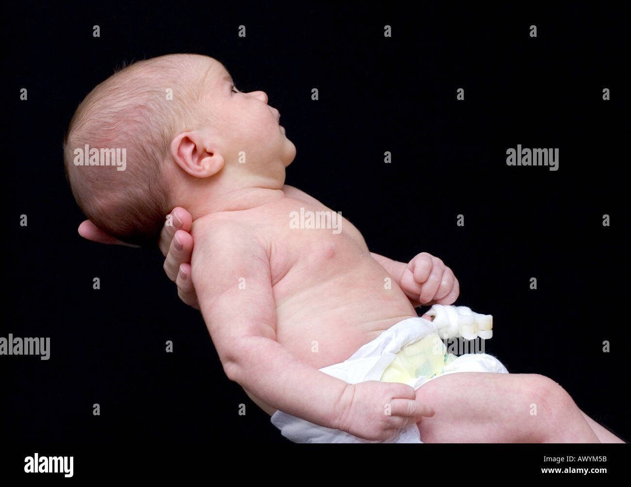 Side view of mother holding newborn baby daughter in nappy against ...
