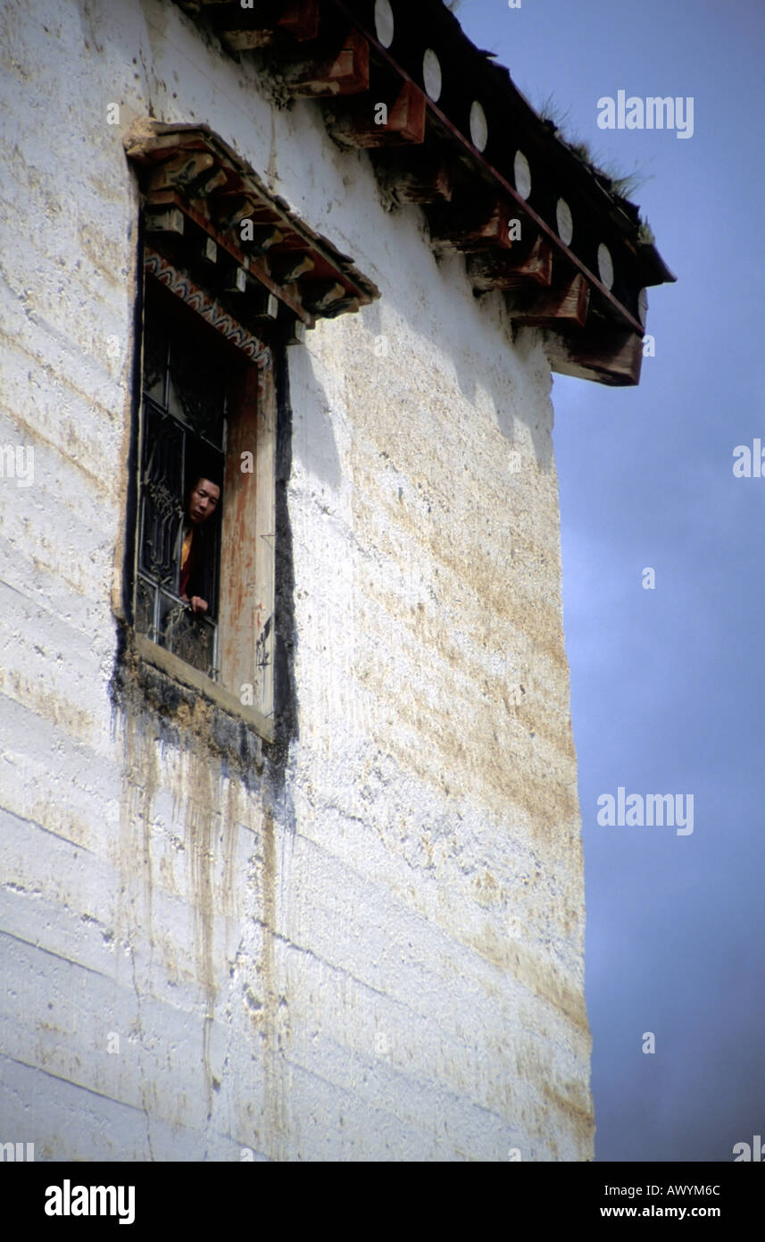 Monk peering out window of Buddhist Tibetan Yellow Hat monastery ...