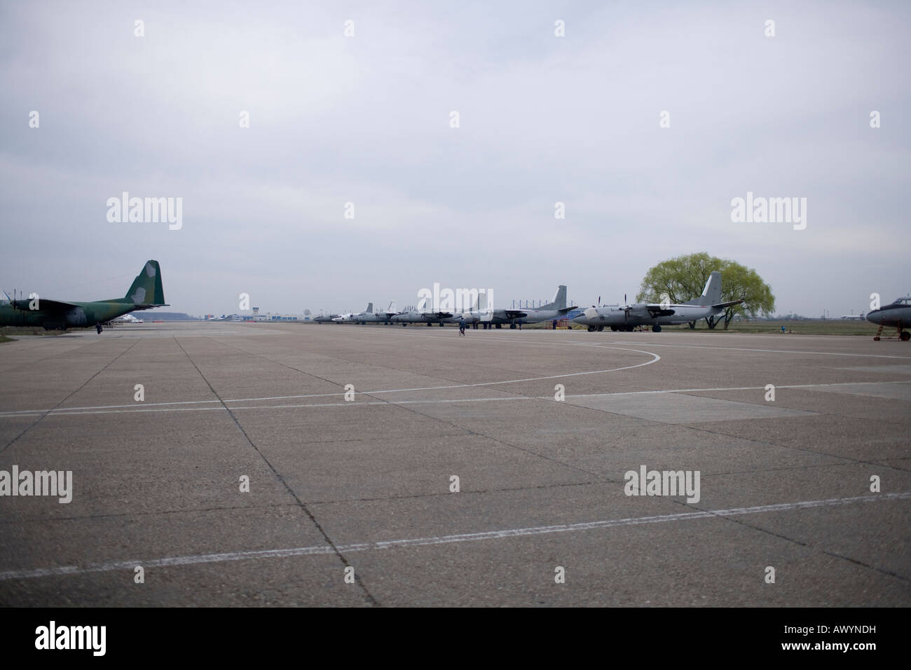 many military airplanes parked on the runway and one is taking off ...