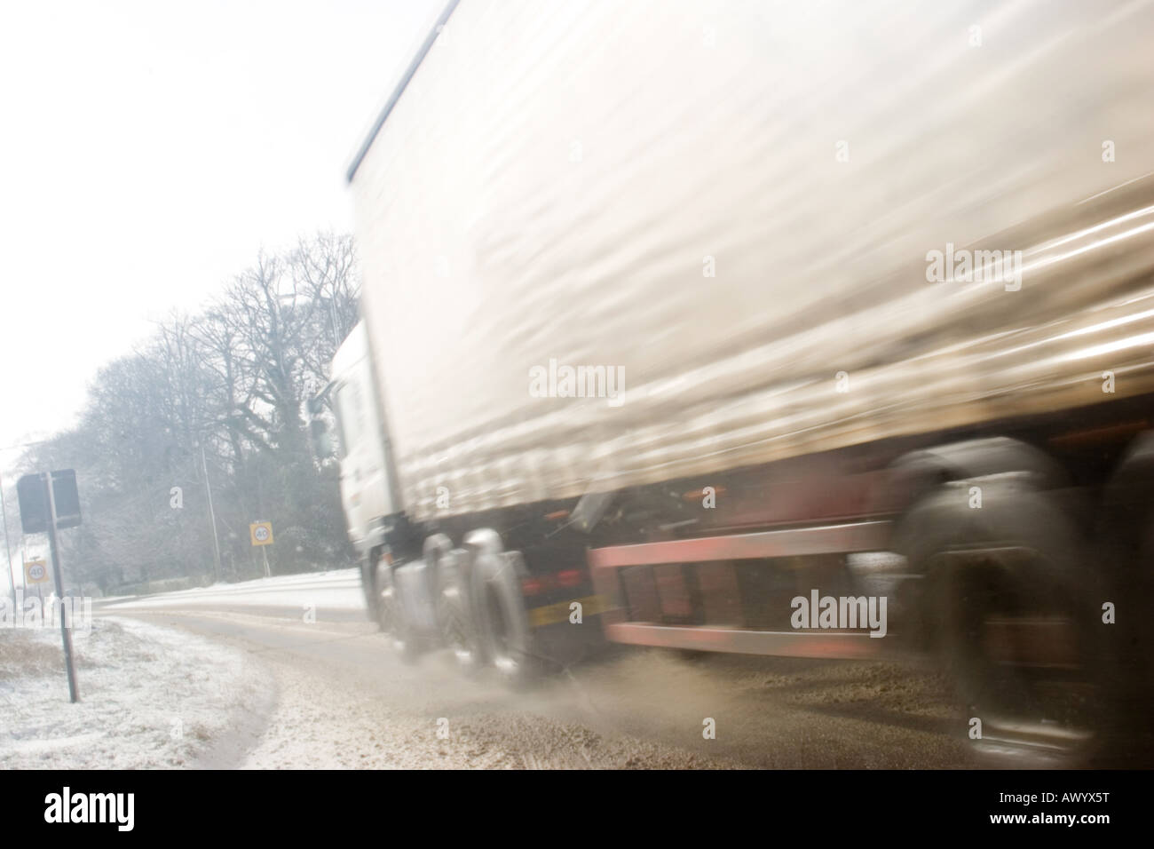 A lorry driving on a road and spraying slush on a snowy winter day ...