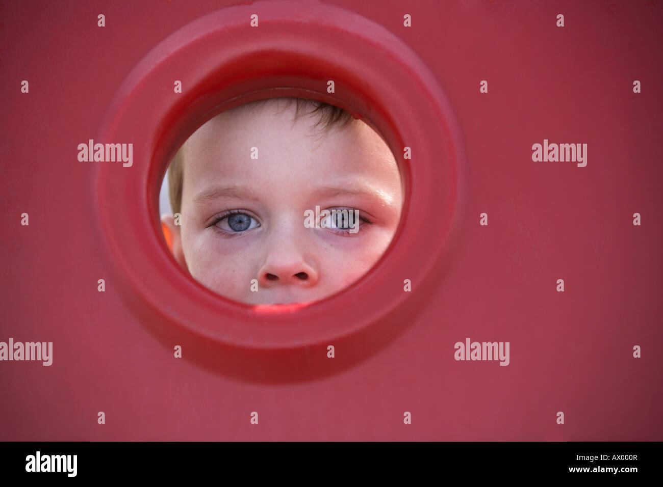 Young boy looking through a hole Stock Photo - Alamy