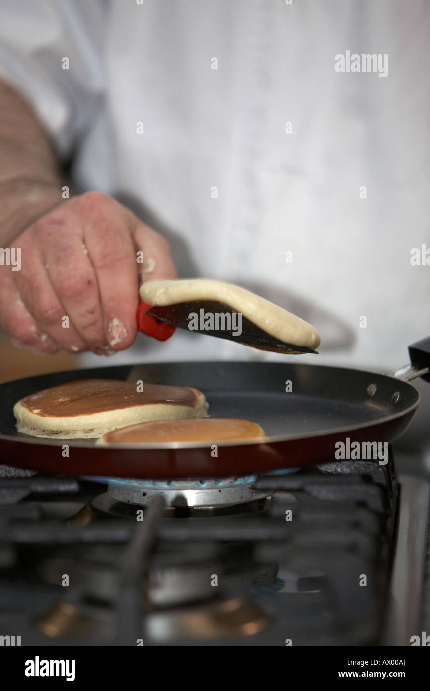 chef turning traditional irish pancakes in a pan on a gas cooker hob ...