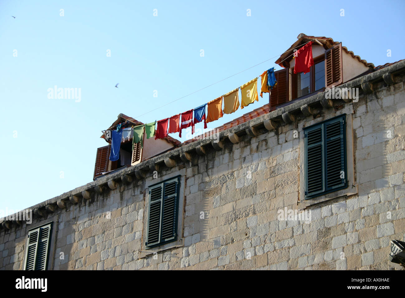 Colourful washing hung between two rooftop windows Stock Photo - Alamy