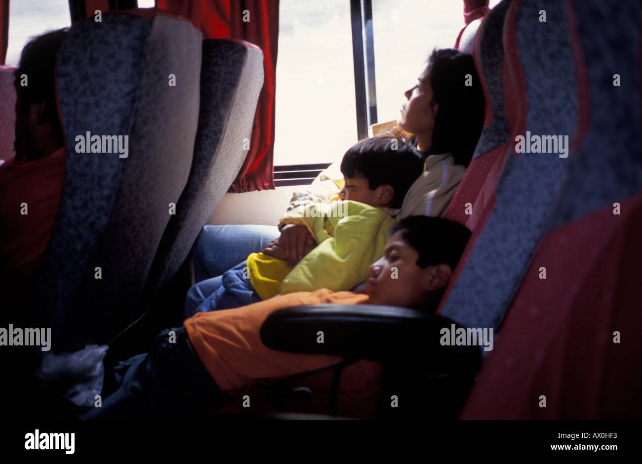 Children sleeping on the bus journey mother looking out of the window ...