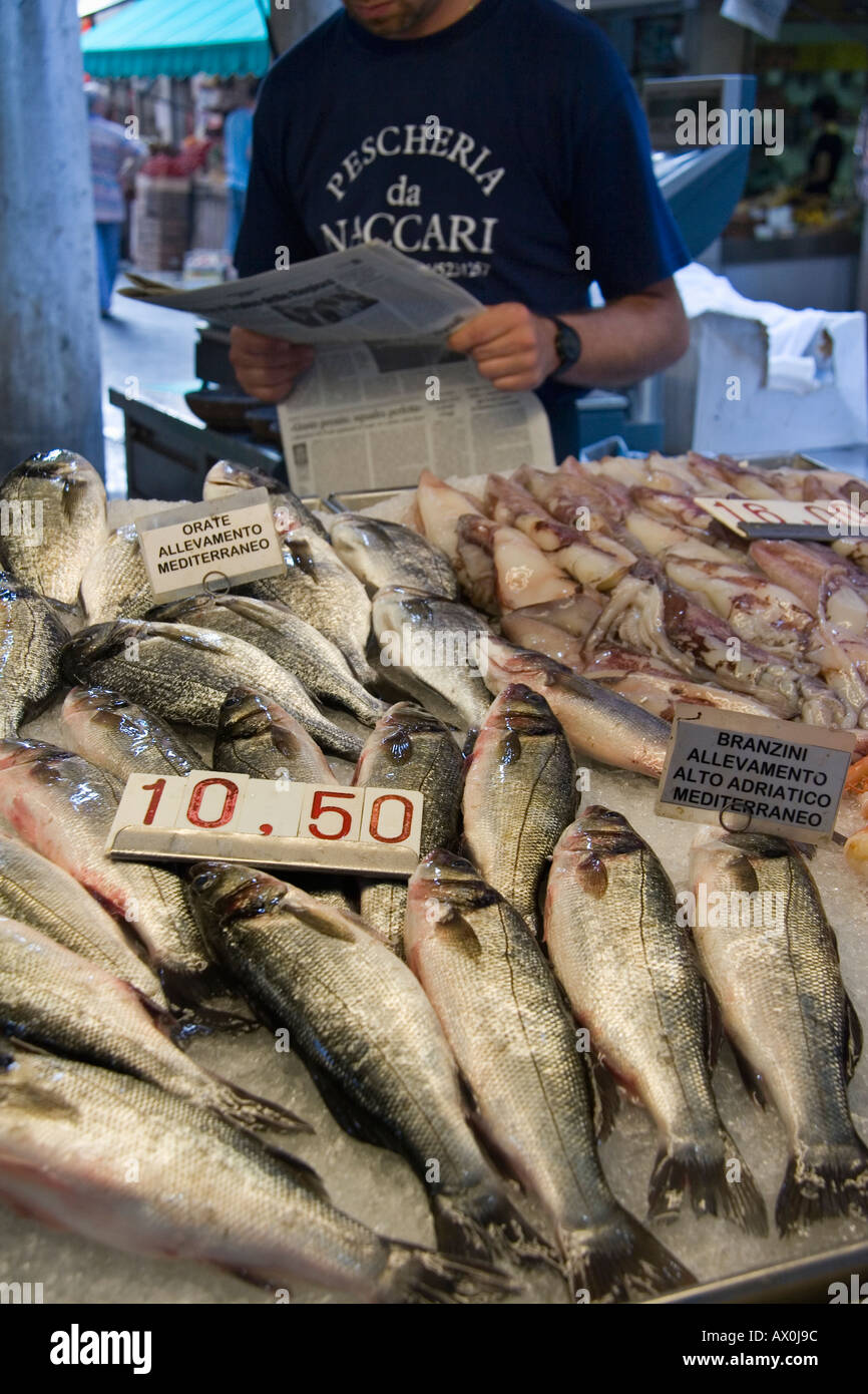 Man reading newspaper behind counter of display of fresh fish at the ...