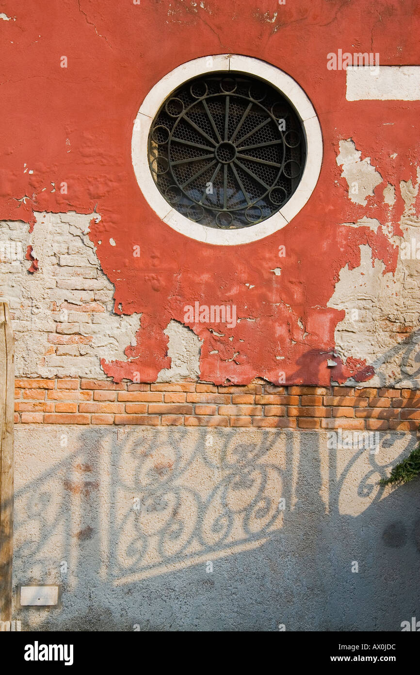 Weathered terra cotta stucco wall with round window and wrought iron ...