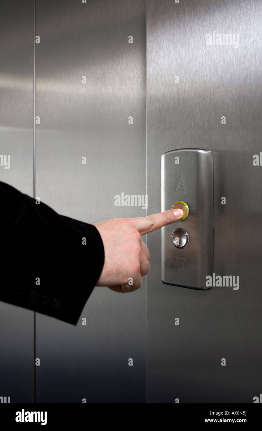 Businessman pushing elevator button Stock Photo - Alamy