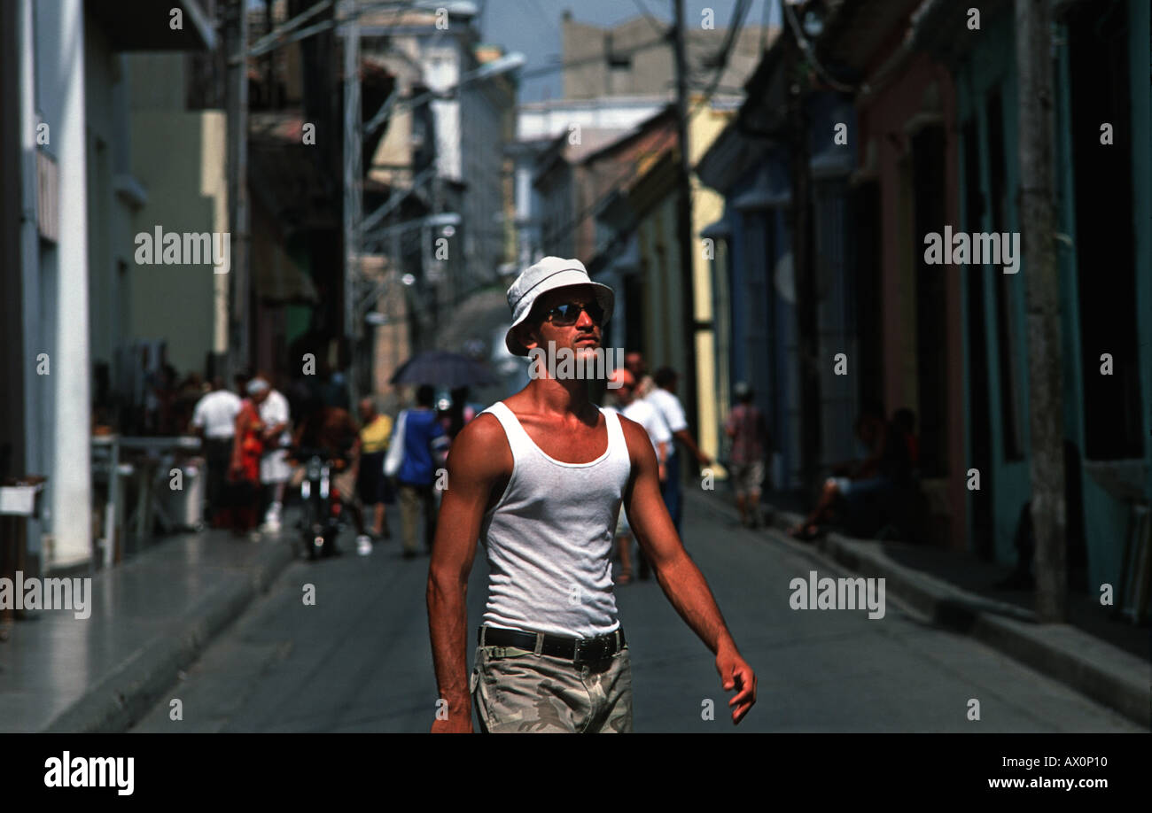 Portrait of a young and trendy Cuban man in cap and shades walking in ...
