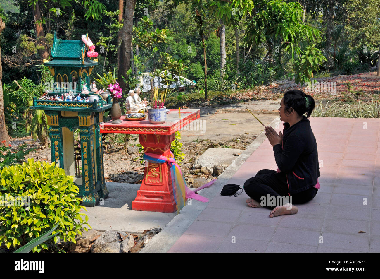 Woman praying on front of a spirit house (san phra phum), Kho Chang ...